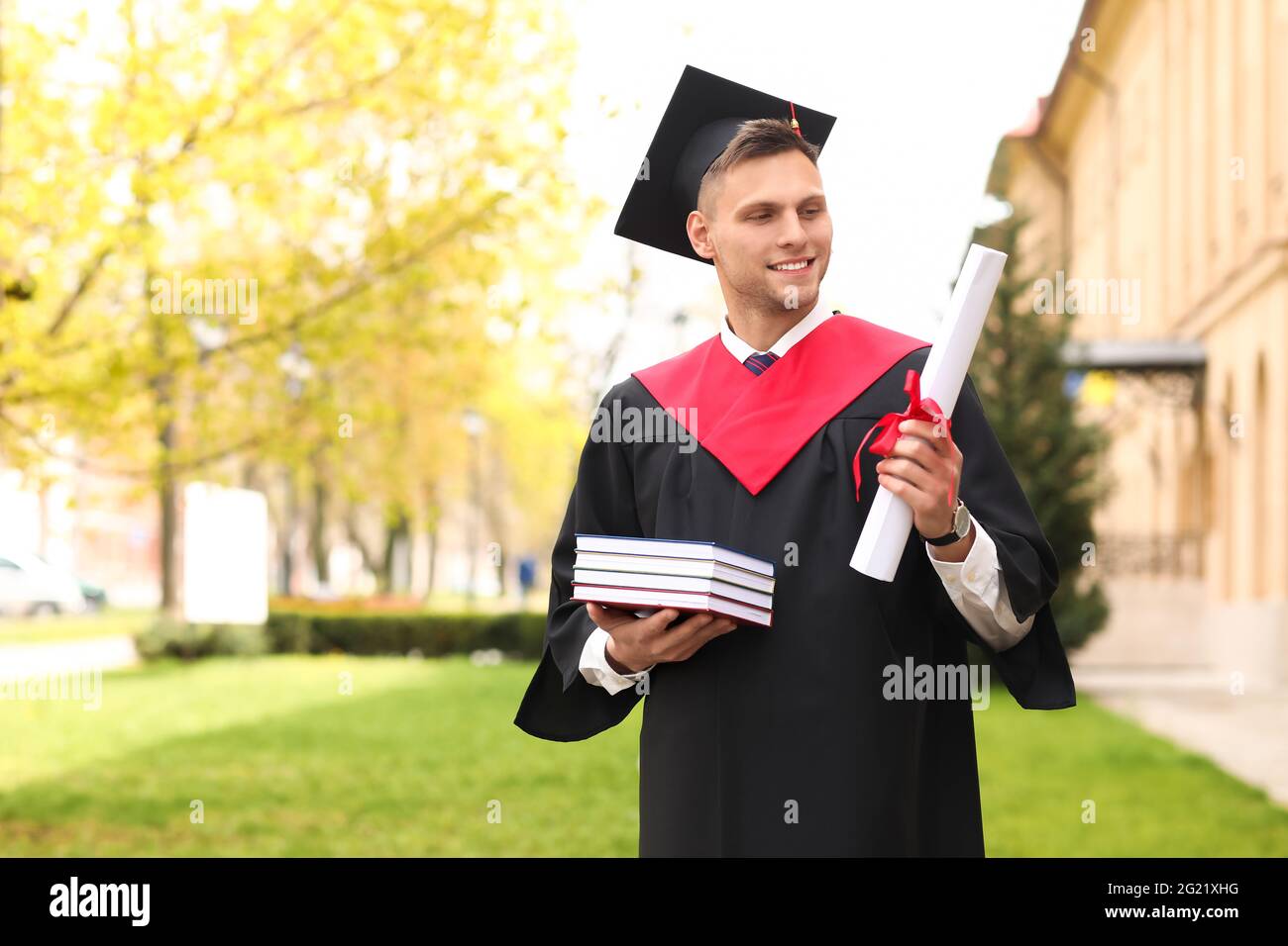 Male graduating student with books outdoors Stock Photo - Alamy