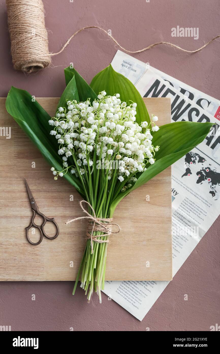Beautiful lily-of-the-valley flowers, scissors and rope on color ...