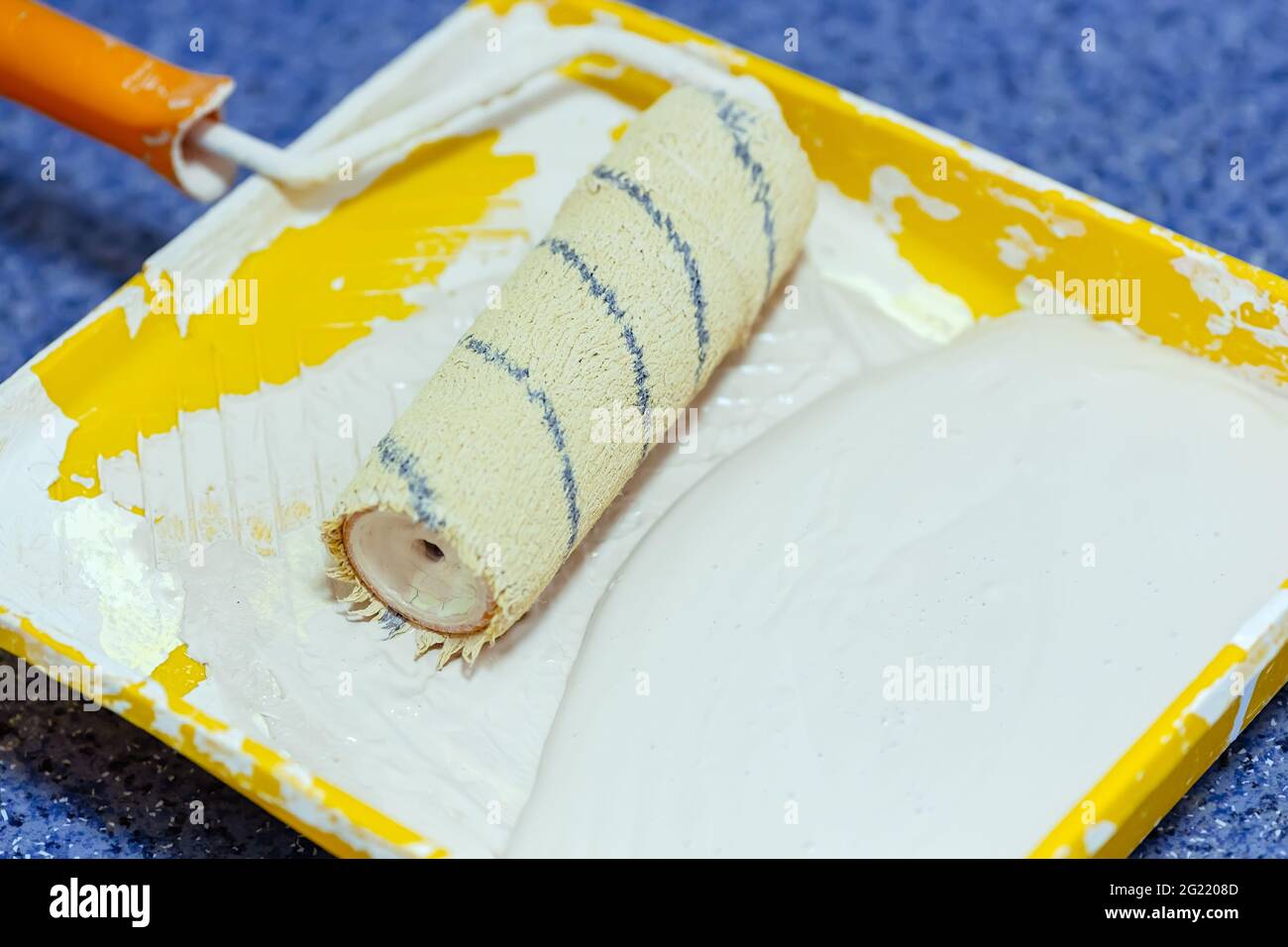 The paint roller is in a yellow tray with beige paint. The concept of ...