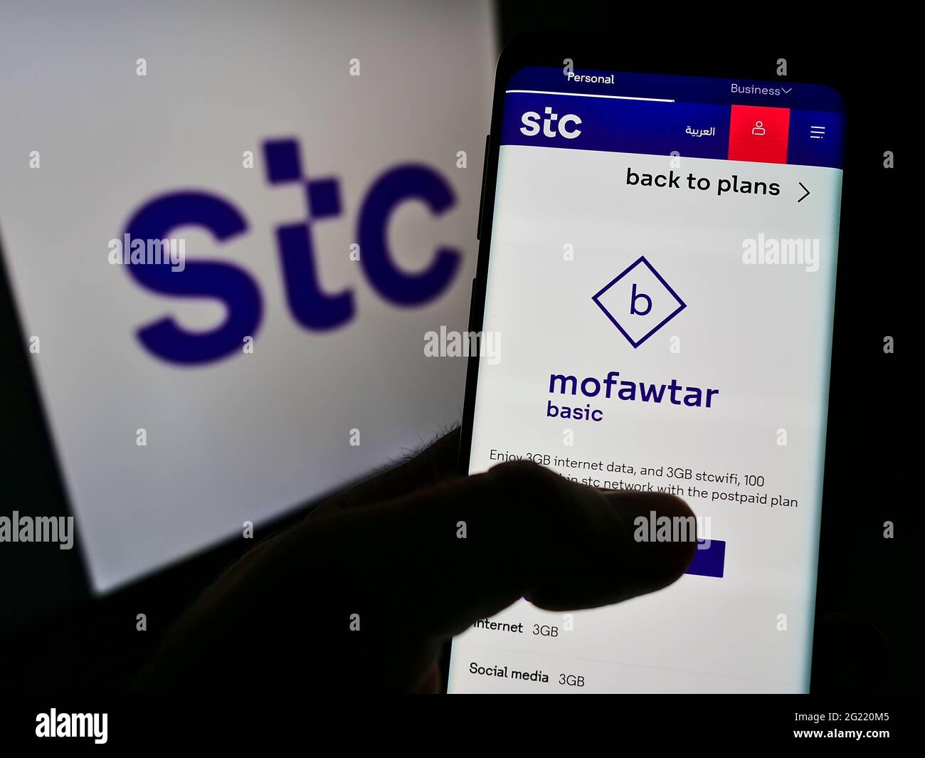 Person holding cellphone with webpage of Arabian carrier Saudi Telecom ...