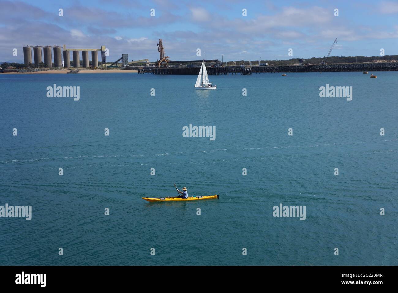 A yellow kayak and a sailboat heading into the blue waters of Mackay ...