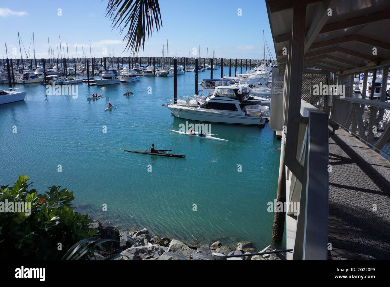 A group in outrigger canoes paddling in the calm water of the small ...