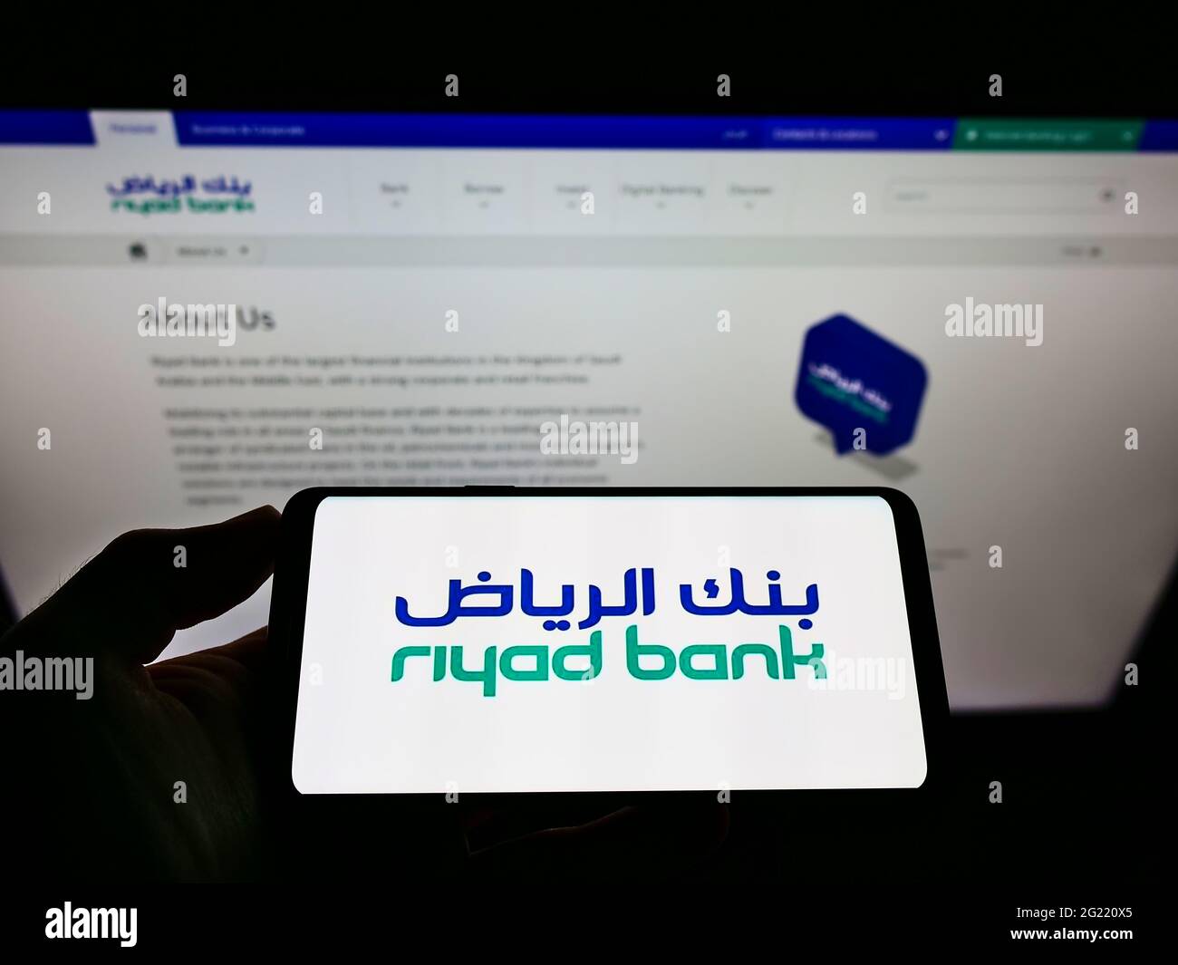 Person holding mobile phone with logo of Saudi Arabian financial ...