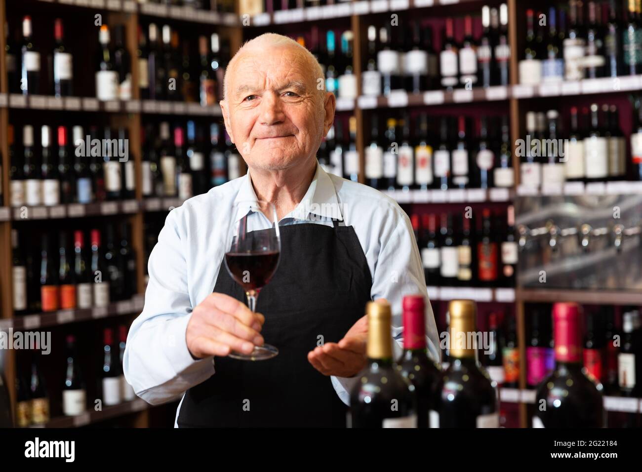 Successful elderly male owner of winery inviting to tasting wine of own ...