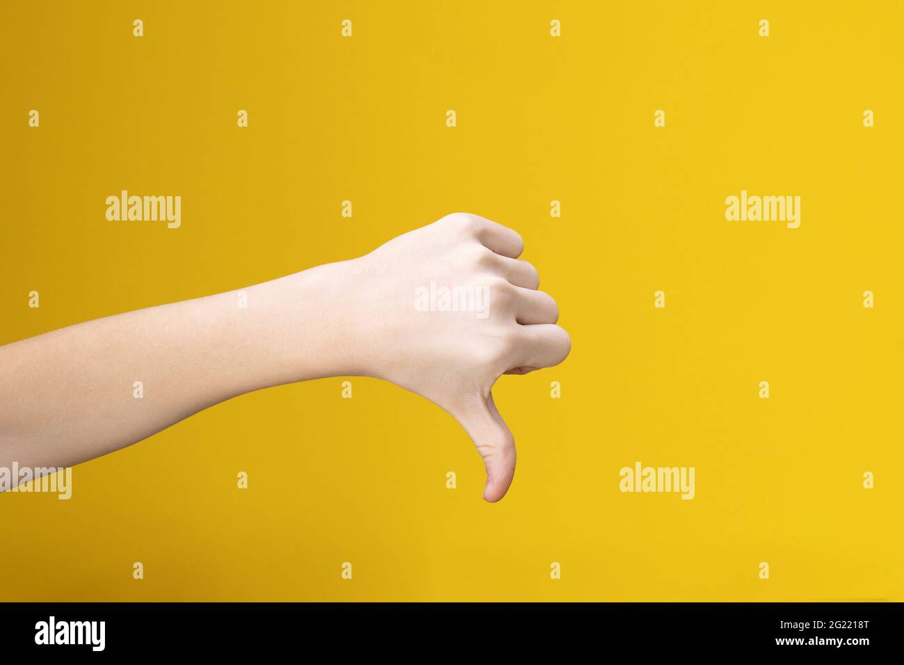 Hand in fist with thumb down gesture on yellow background. Sign, icon ...