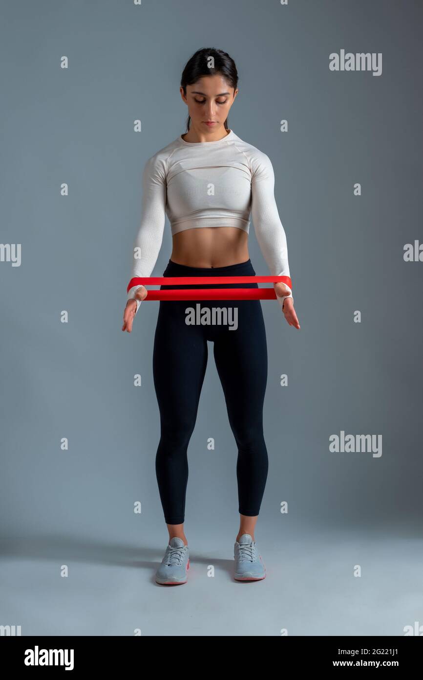 Girl doing arm exercises with resistance band on grey background Stock ...