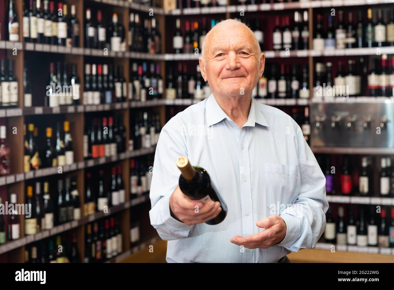 Elderly man chooses red wine in a liquor store Stock Photo - Alamy