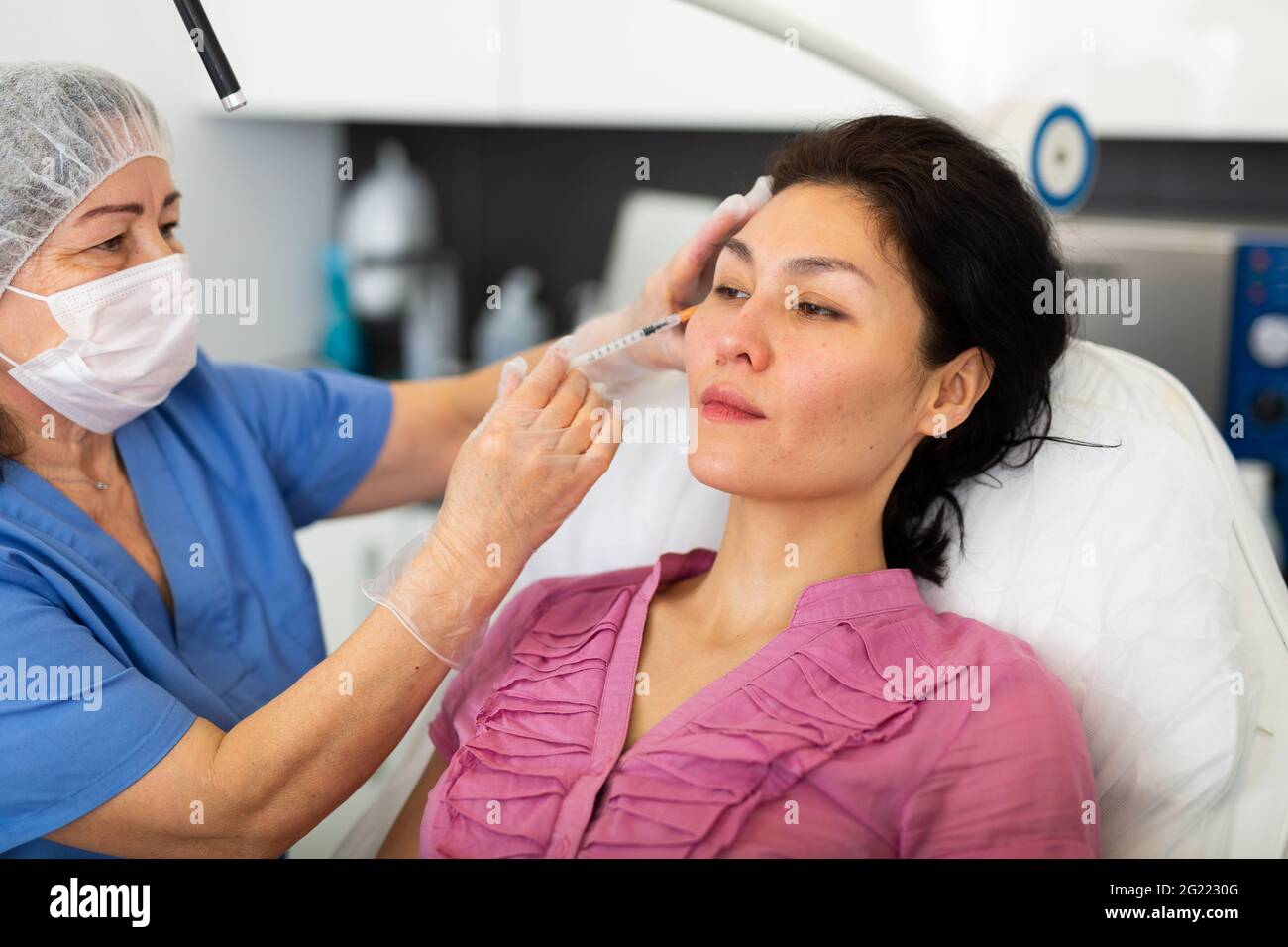 Asian woman getting facial injections at aesthetic cosmetology clinic ...