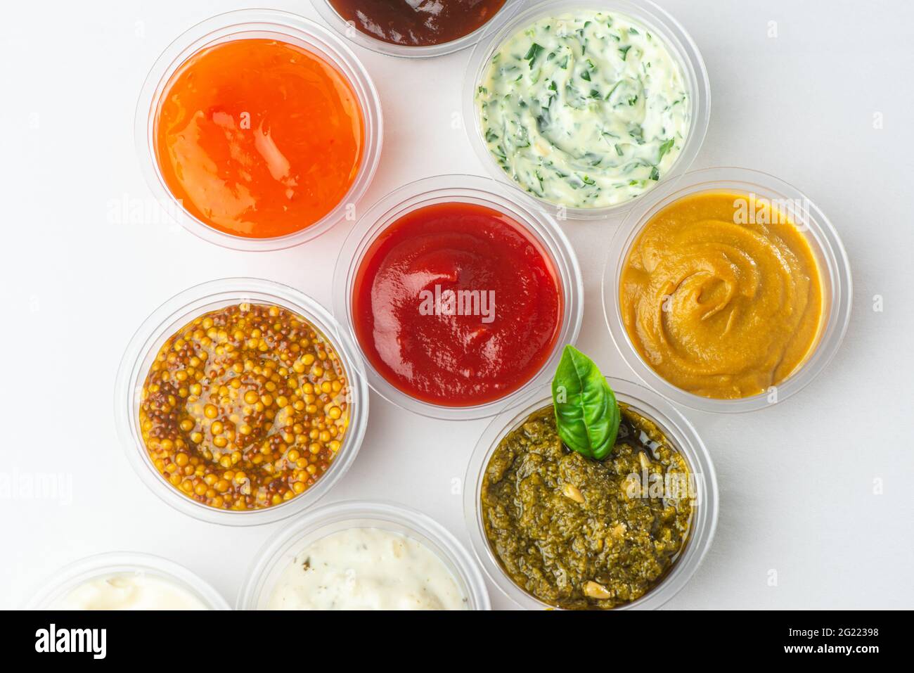 Top view on cups of assorted sauces and condiments on white background ...