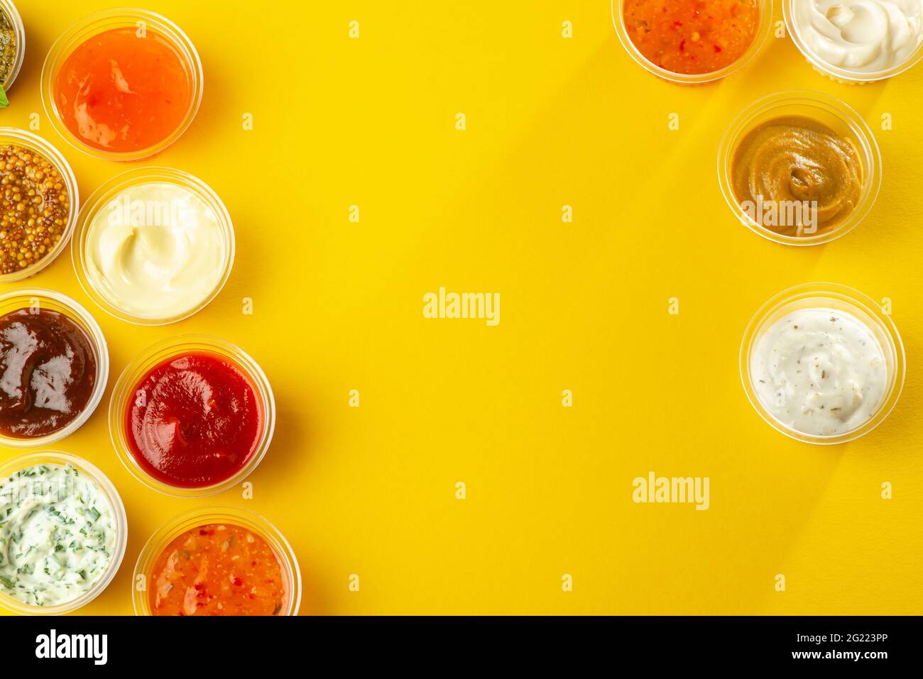 Assorted sauces in small cups on yellow background with copy space ...