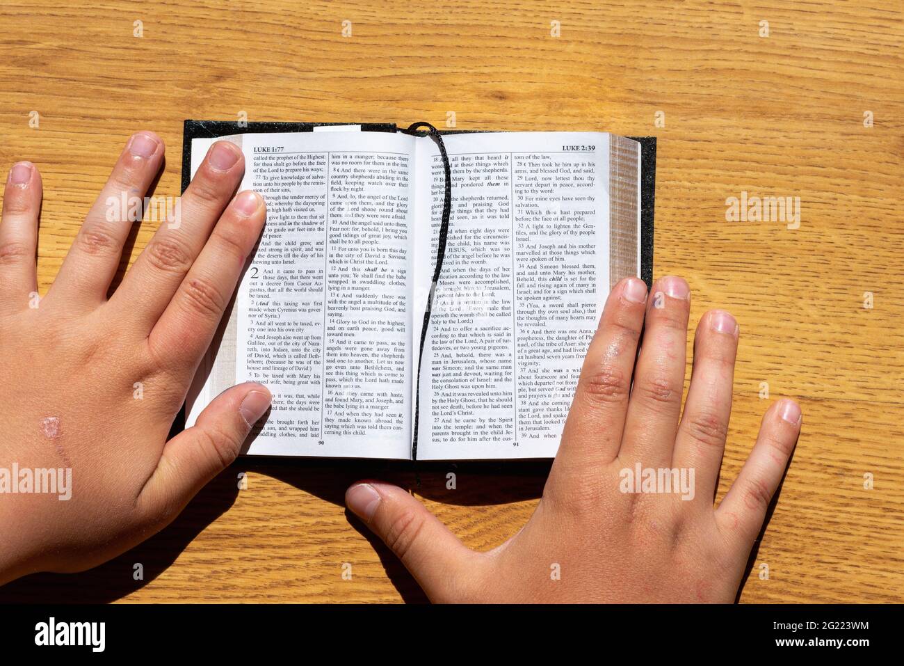 Childs hands hold a bible leaning on a wooden table. Small Book Holy ...
