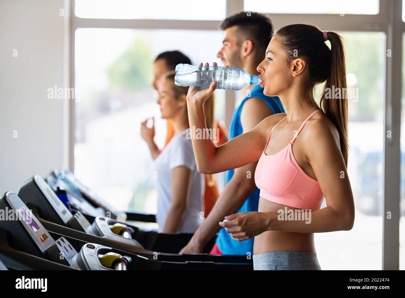 Happy young fit woman drinking during workout, running in the gym Stock ...
