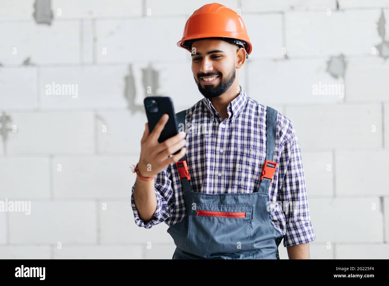 Indian builder checking a message on his mobile phone or making a call ...