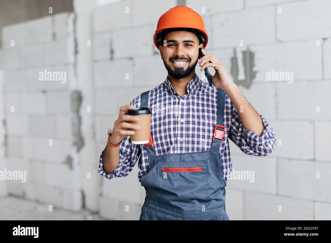 Professional young bricklayer talking by smartphone on the construction ...