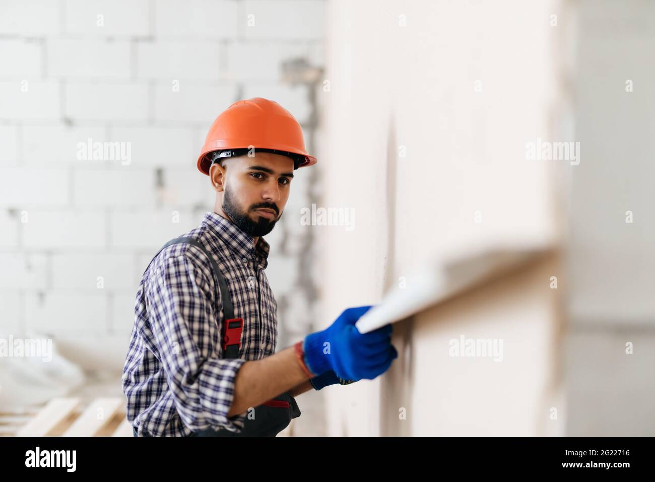 Indian builder at facade plastering work during industrial building ...