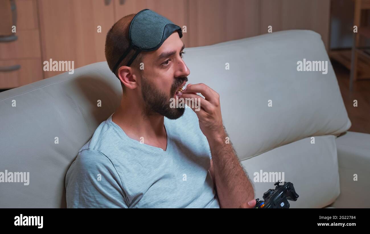 Pro gamer with sleep mask sitting in front of television playing ...