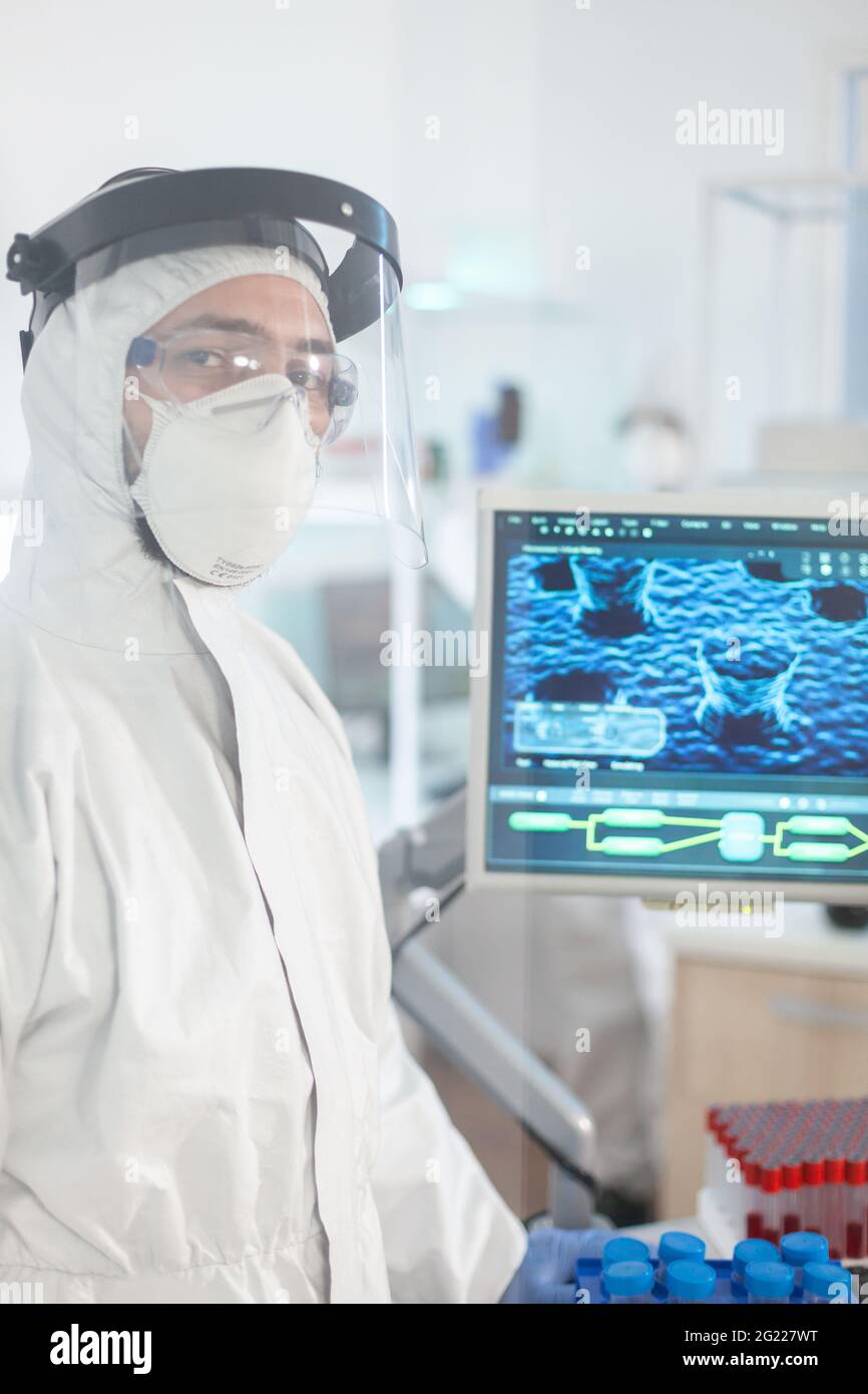 Microbiologist in ppe suit standing in laboratory looking at camera ...