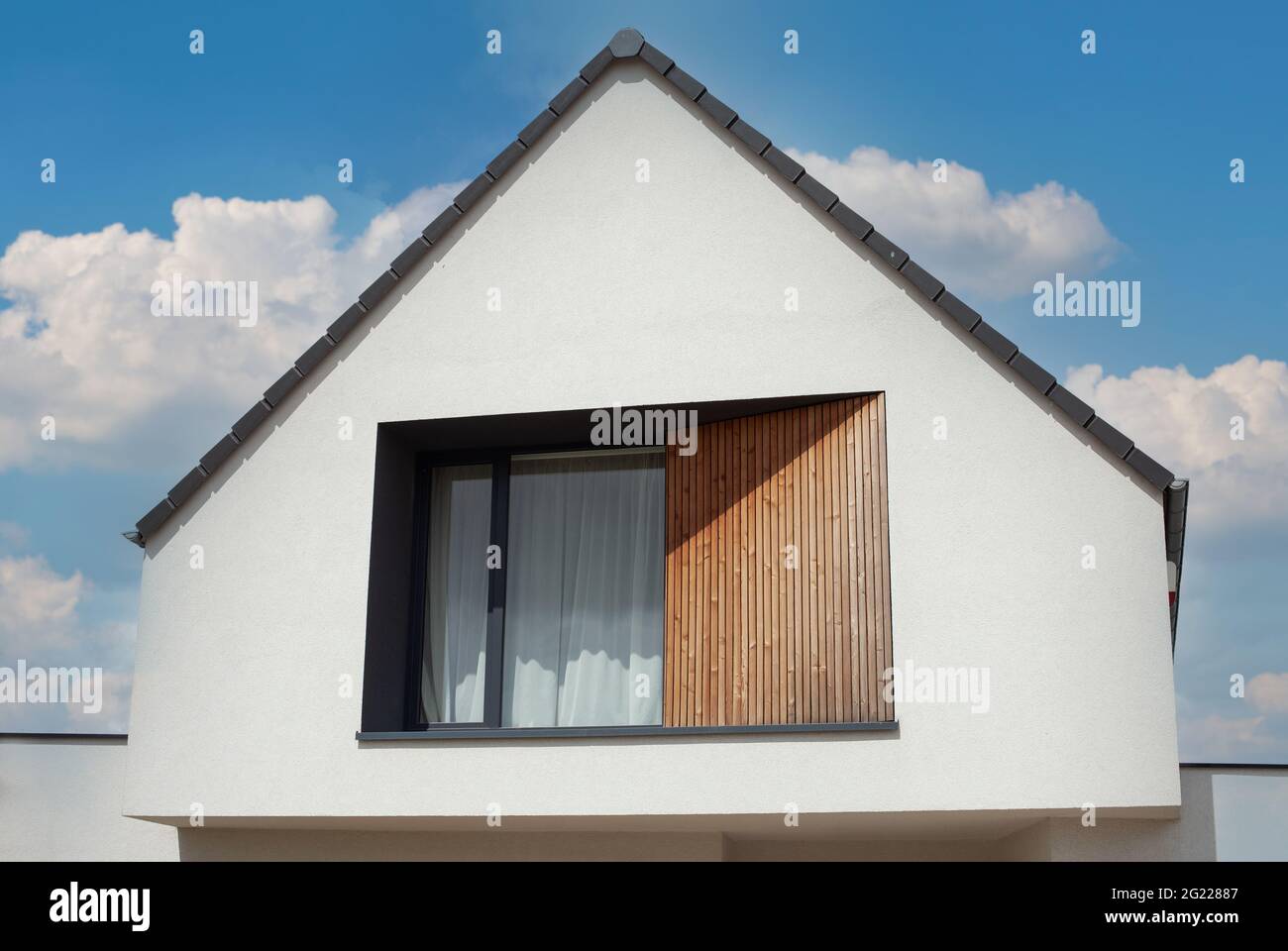 Closeup shot of a gable roof with a single window and black triangular ...