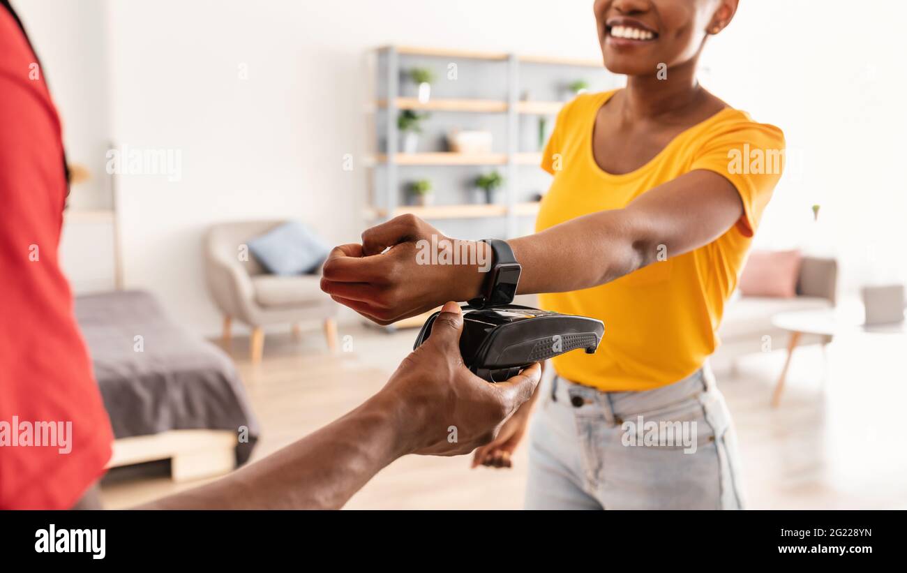 Courier Giving Terminal To Customer Paying With Smartwatch At Home ...