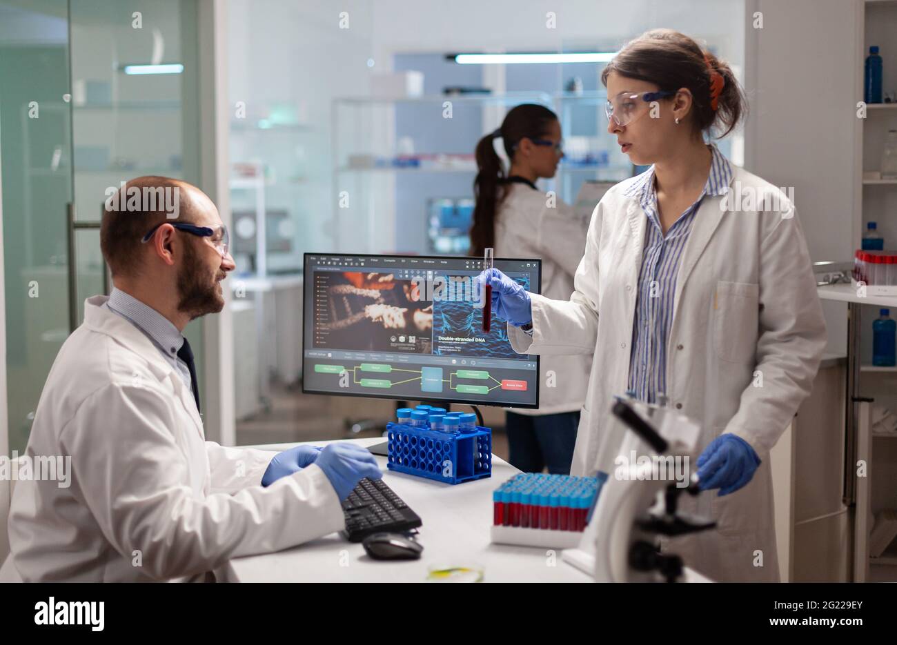 Medical chemists disscussing about vaccine development holding test ...