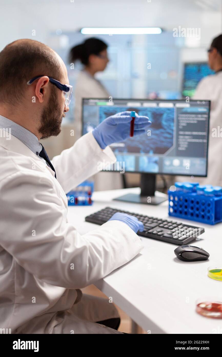 Genetic scientist studying epidemics holding sample of blood in test ...