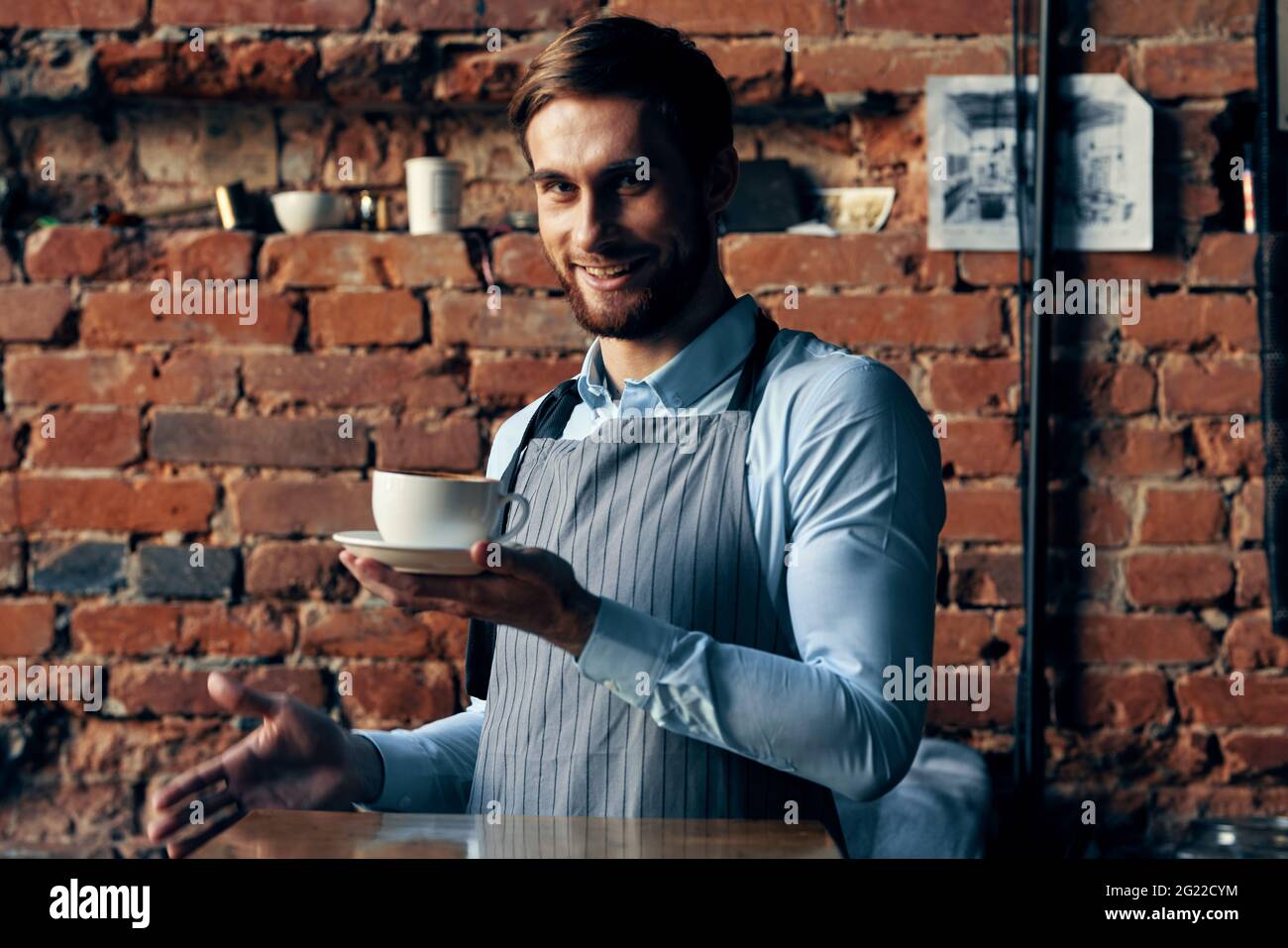 male waiter wearing apron coffee cup service lifestyle Stock Photo - Alamy