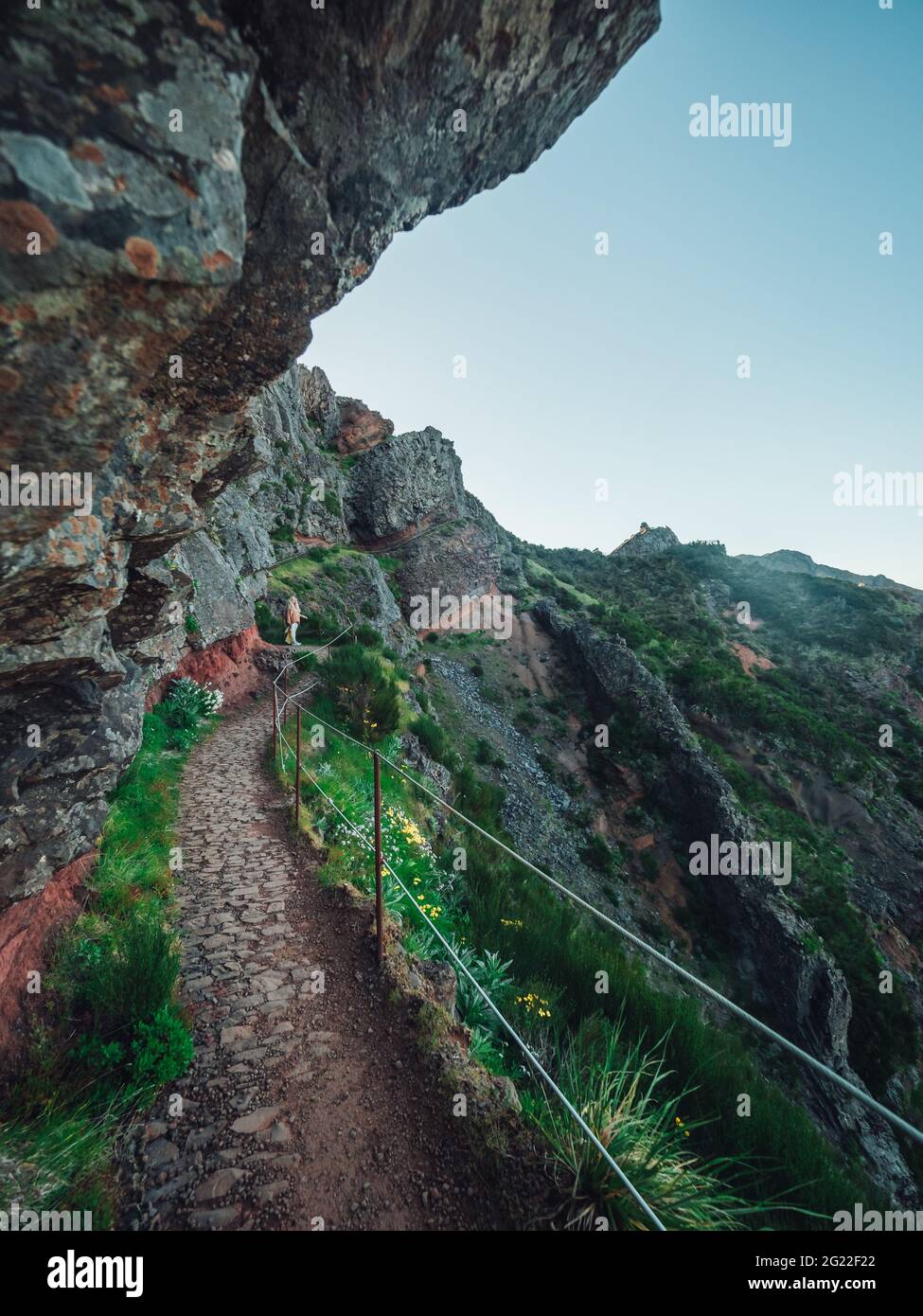Vertical shot of a blonde woman hiking on a trail in the mountains ...