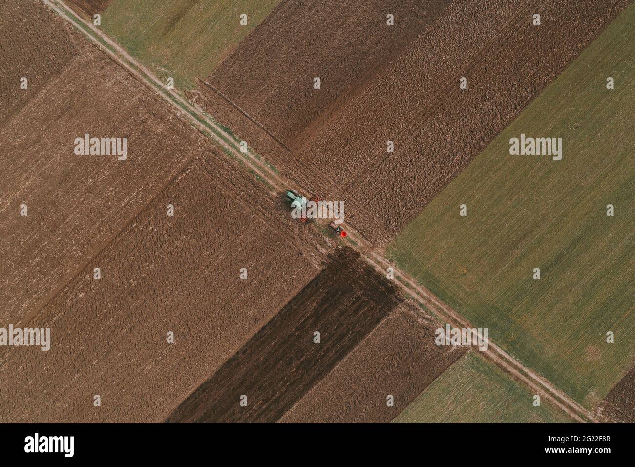 Aerial view of two farm tractors tilling in cultivated fields, drone ...
