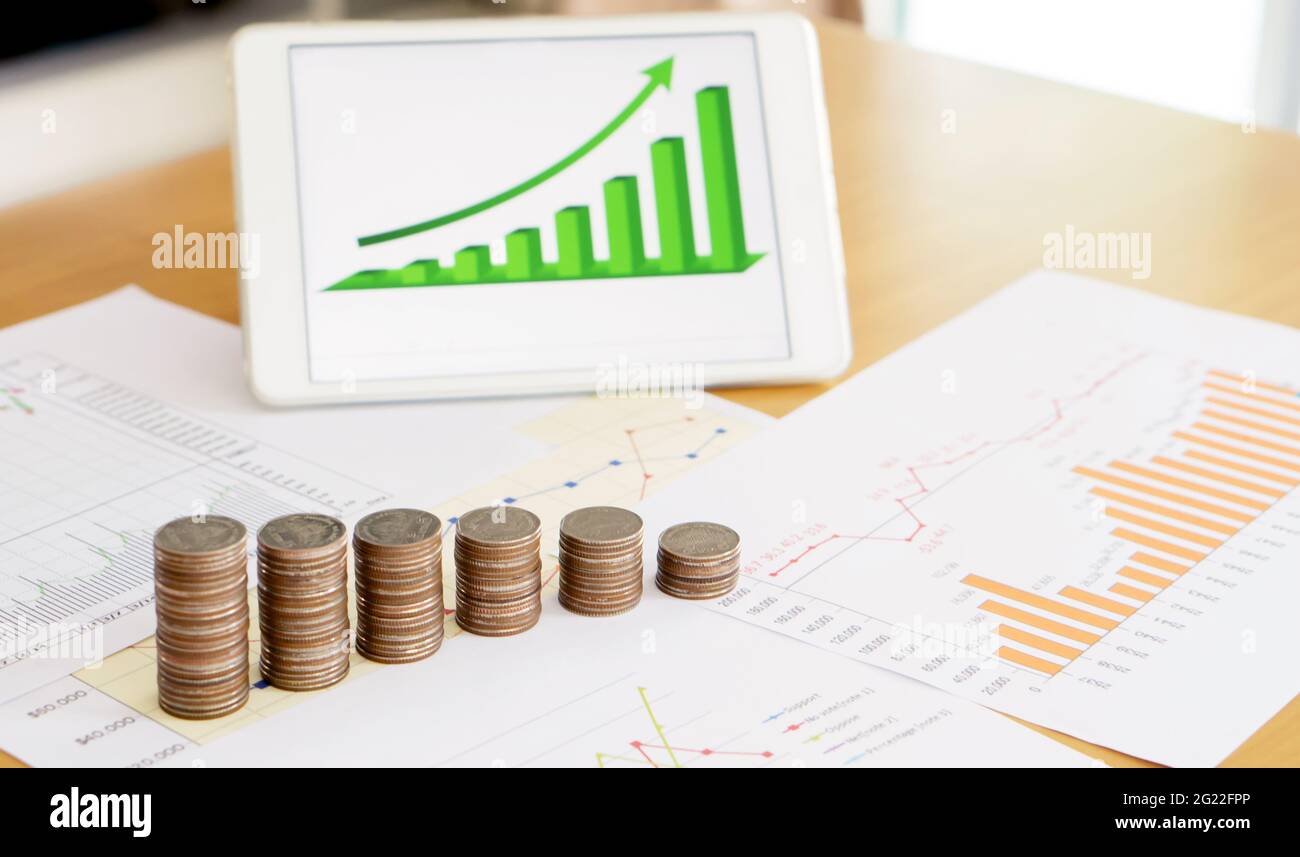 Grow up coins stack with business and finance graph screen on laptop ...