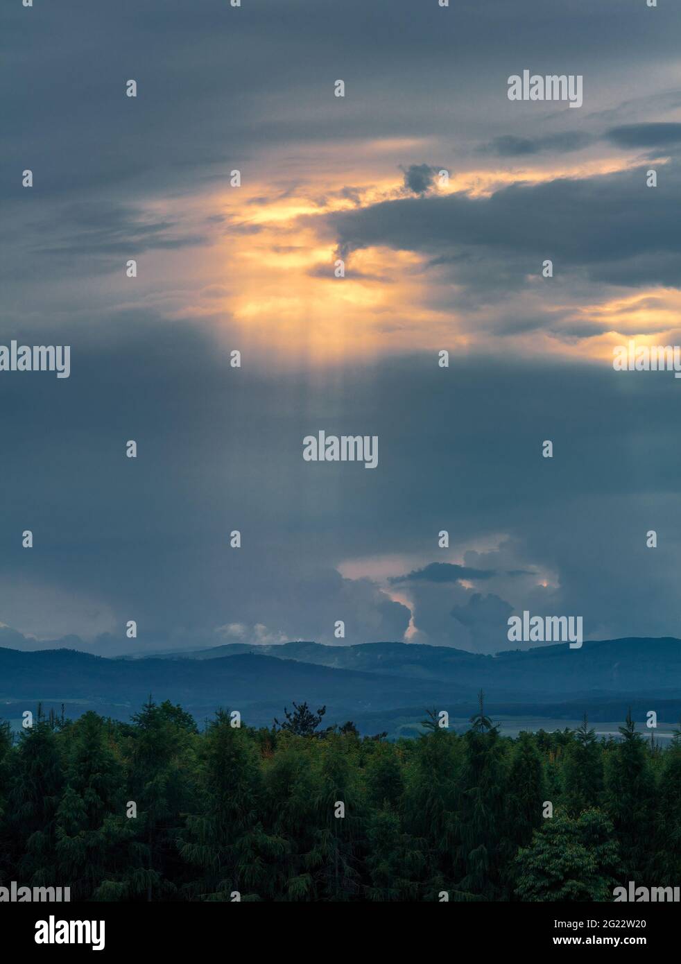 Dramatic sky with god light over forest and distant hill. Czech ...