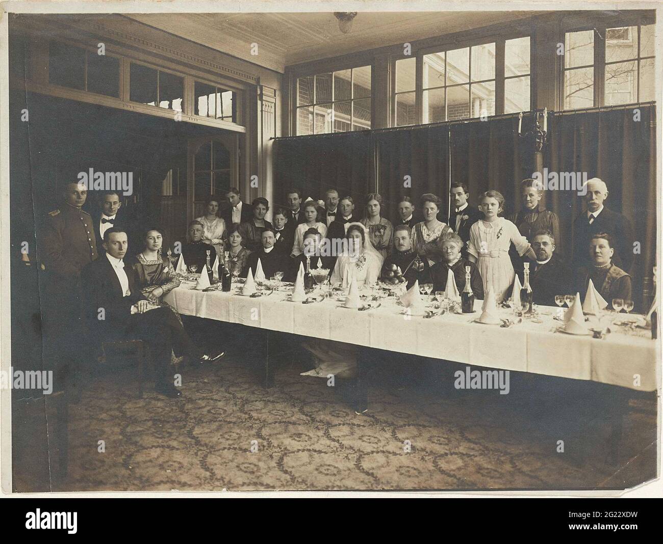 Wedding couple and guests on and around table Stock Photo - Alamy