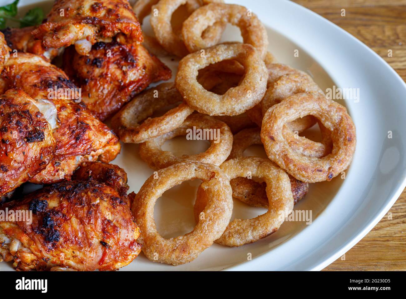 Peri peri chicken thighs and onion rings Stock Photo - Alamy