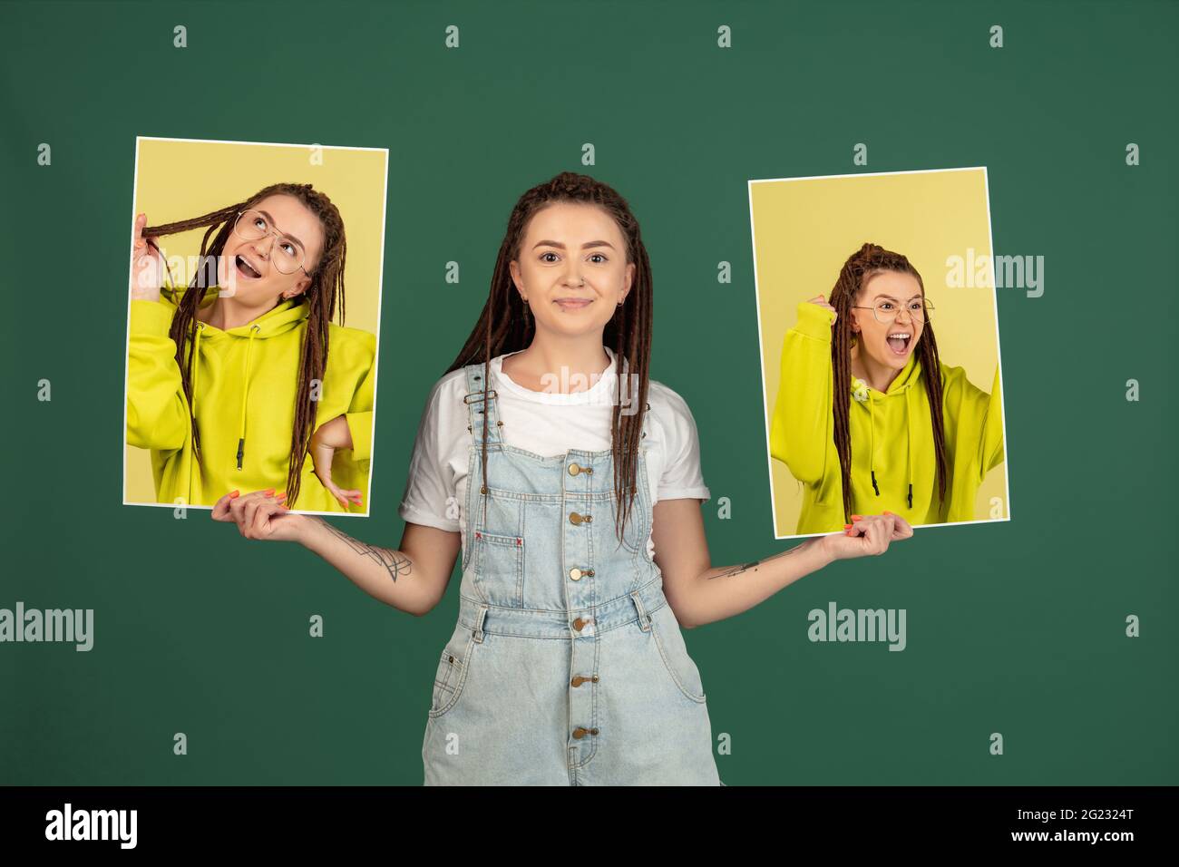 Young girl holding her portraits isolated over green studio background ...