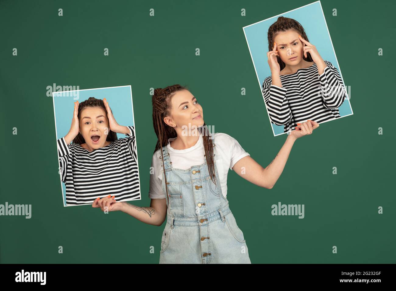 Young girl holding her portraits isolated over green studio background ...