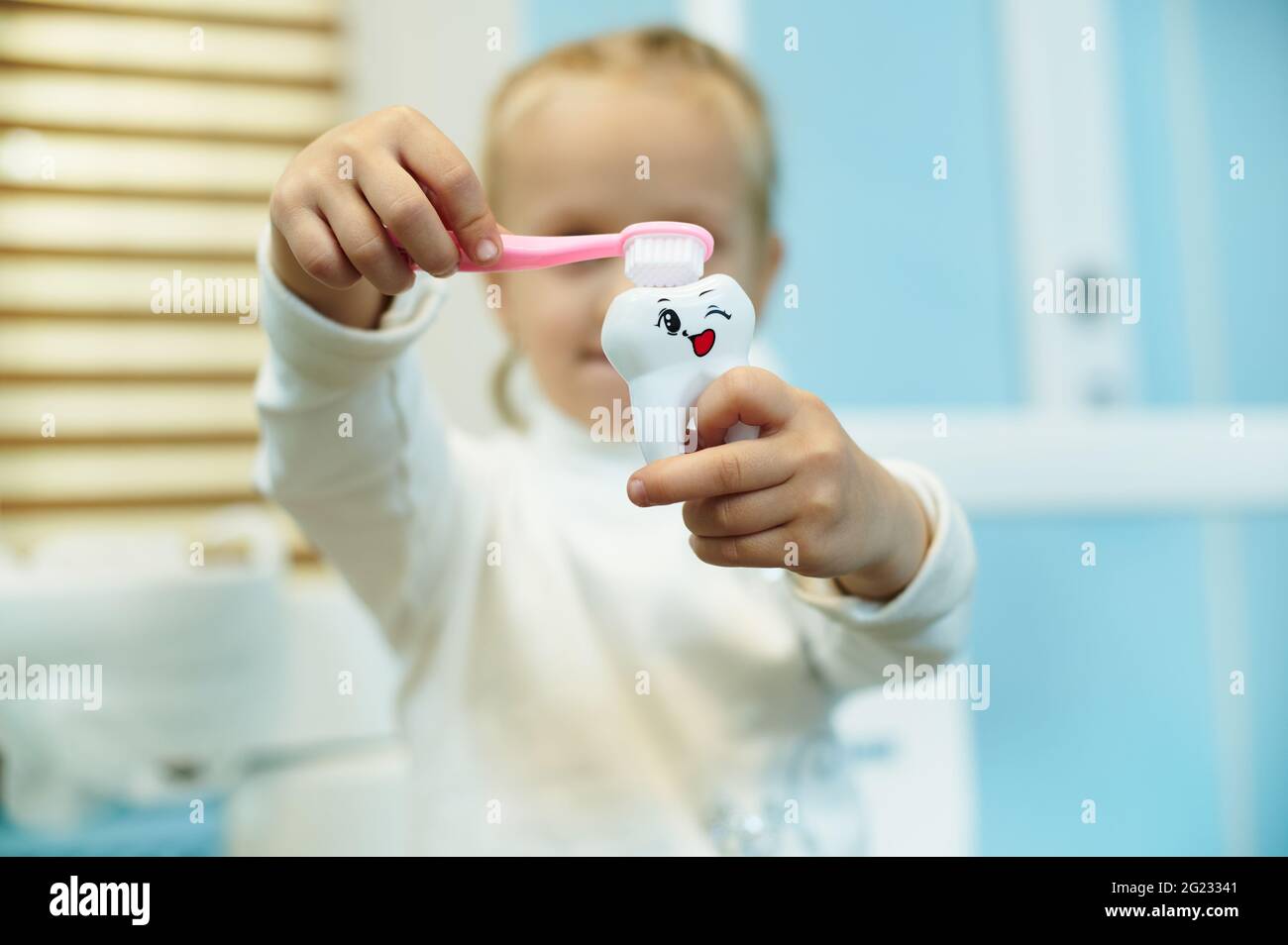 Adorable child brushing a white toy tooth with a toothbrush in the ...