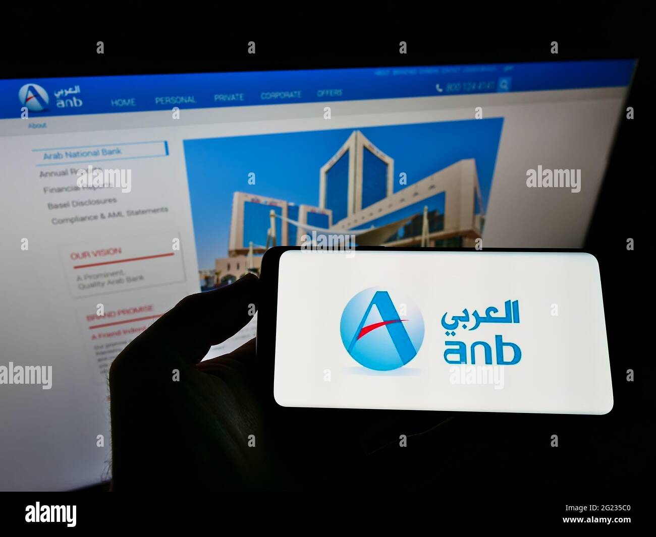 Person holding mobile phone with logo of Saudi Arabian financial ...