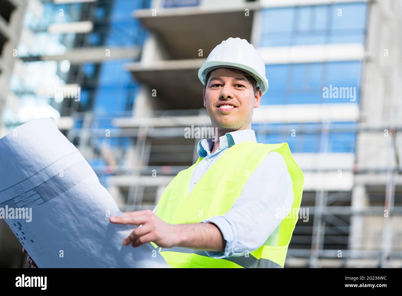 Construction engineer studying floor plan in front of building shell at ...
