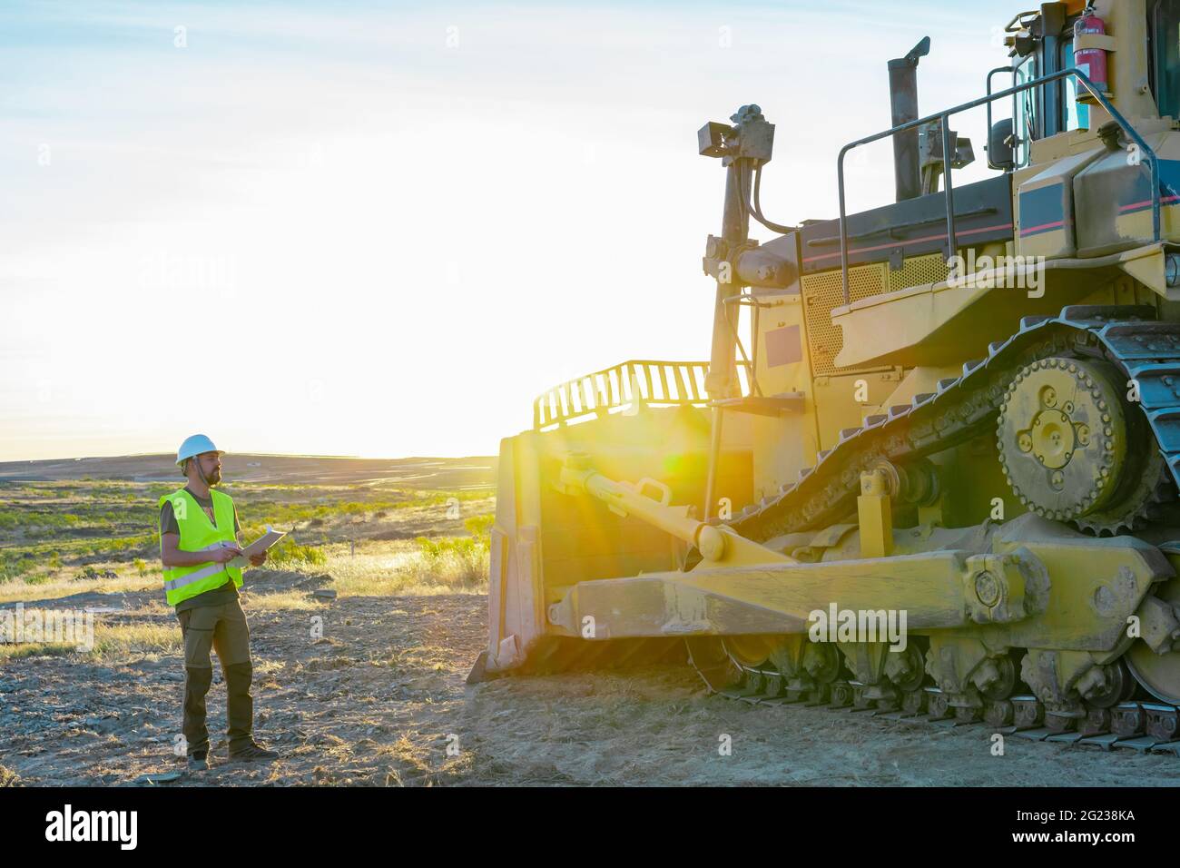 Construction worker inspecting a heavy machine, bulldozer. large ...