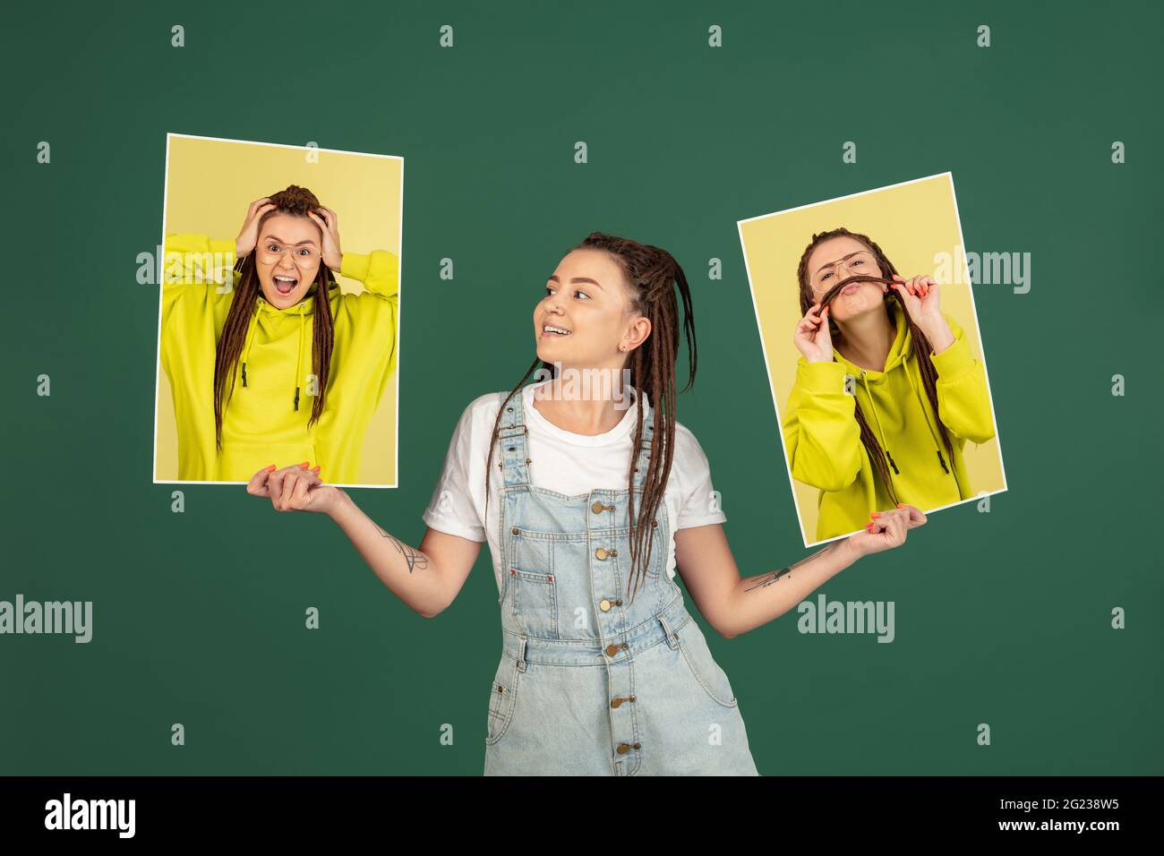 Young girl holding her portraits isolated over green studio background ...