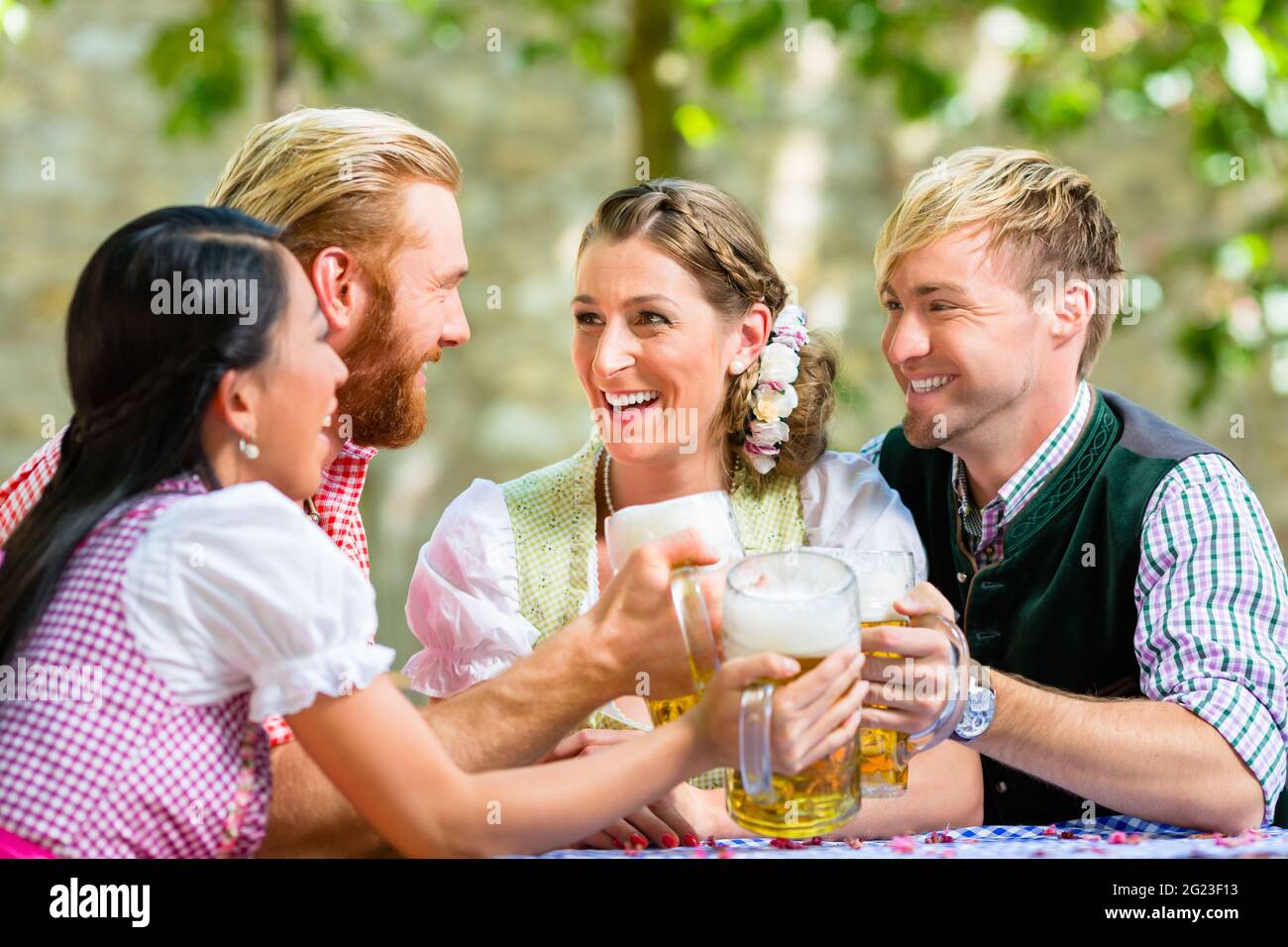 In beer garden - friends in Bavarian clothes drinking beer in Bavaria ...