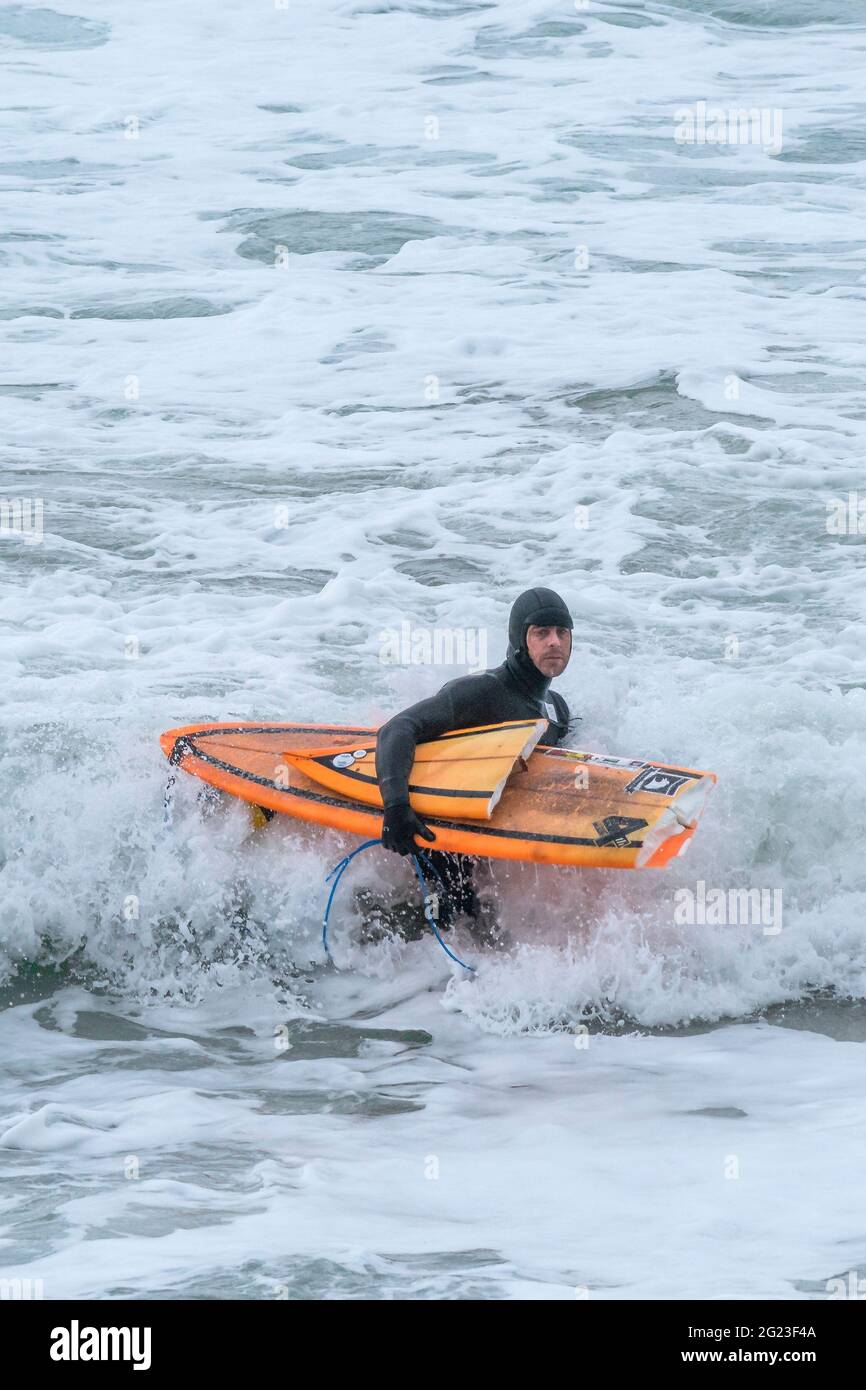 A surfer standing in the rough sea with a snapped surfboard at Little ...