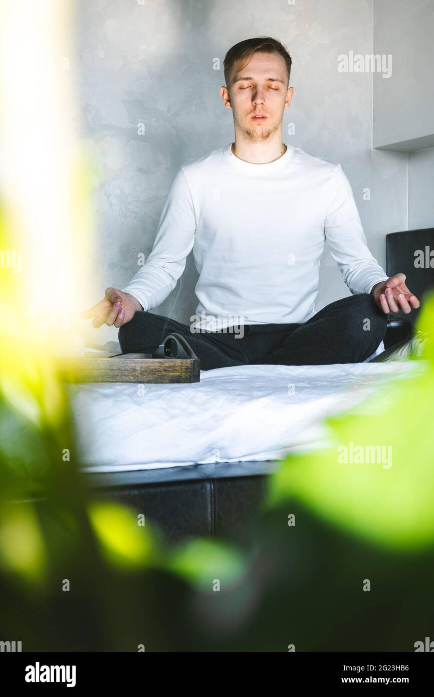 Man Sitting On Bed At Home Meditating after waking up in morning ...