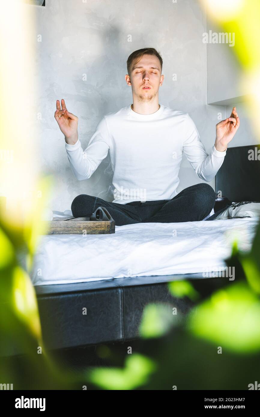 Man Sitting On Bed At Home Meditating after waking up in morning ...