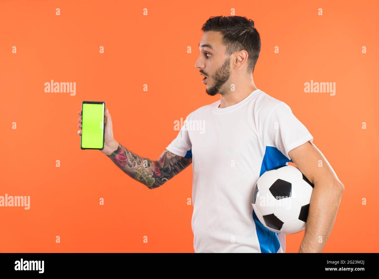 Surprised man football player looking at smartphone with green screen ...
