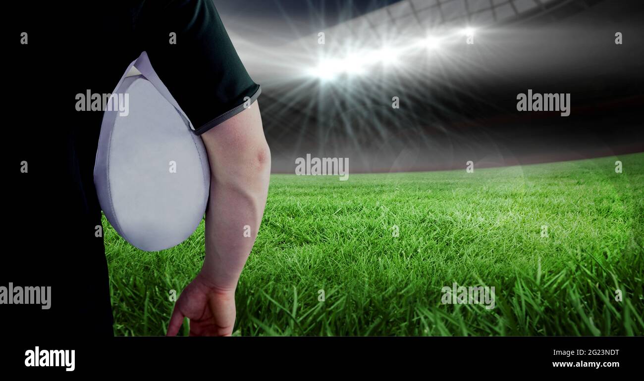 Mid section of caucasian male rugby player holding a rugby ball against ...