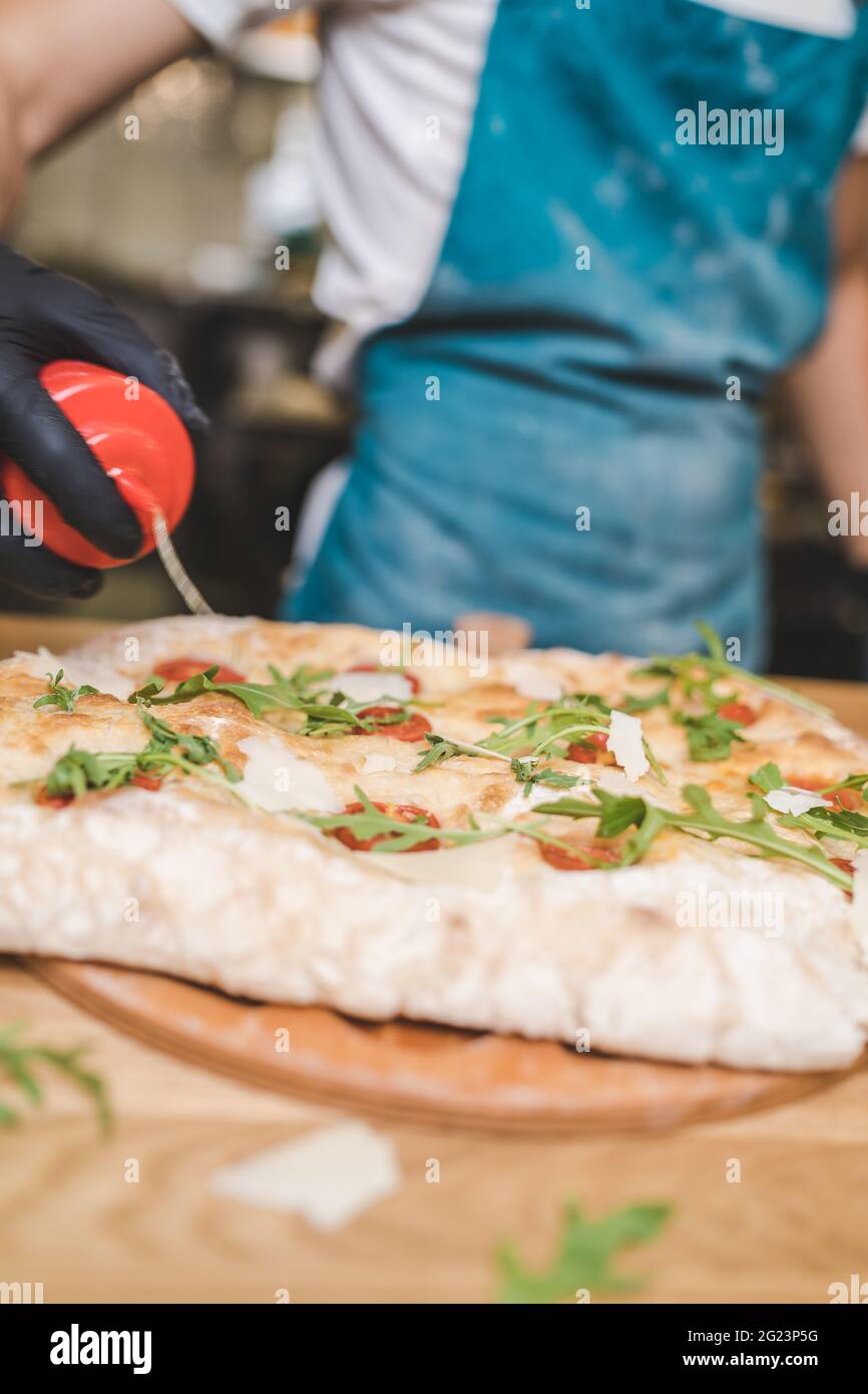 Chef making pizza in restaurant. Fresh made pizza with cherry tomatoes ...