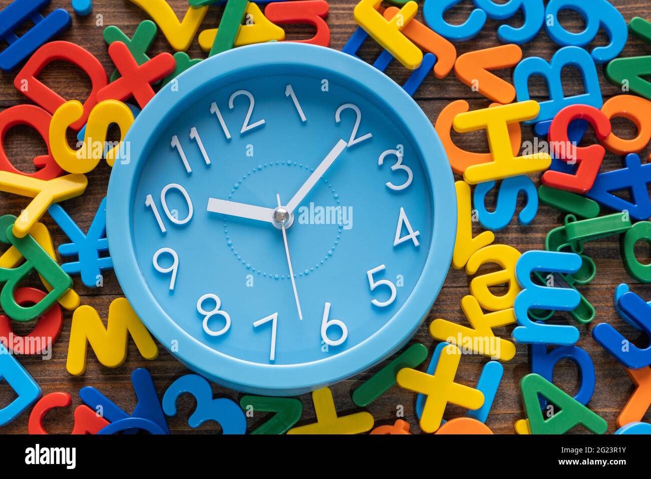 Blue alarm clock with colorful alphabet on wooden background Stock ...