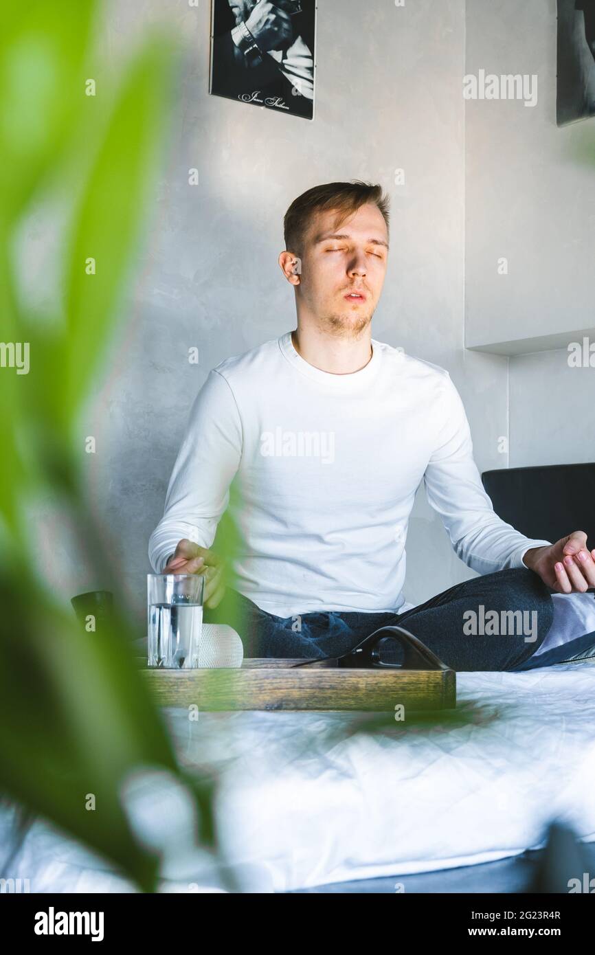 Man Sitting On Bed At Home Meditating after waking up in morning ...