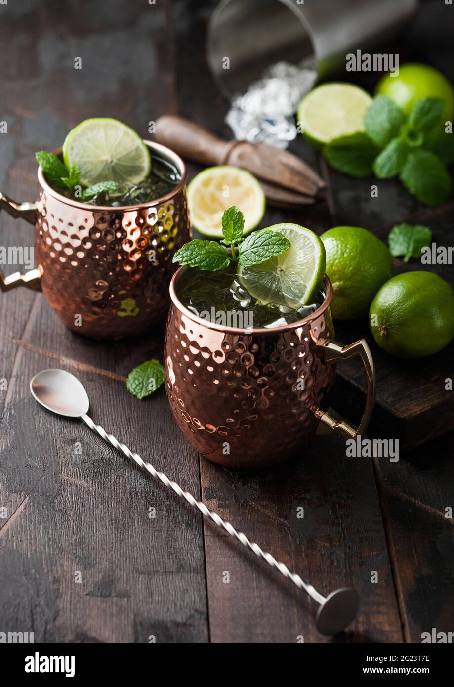 Moscow mule cocktail in a copper mug with lime and mint and wooden ...