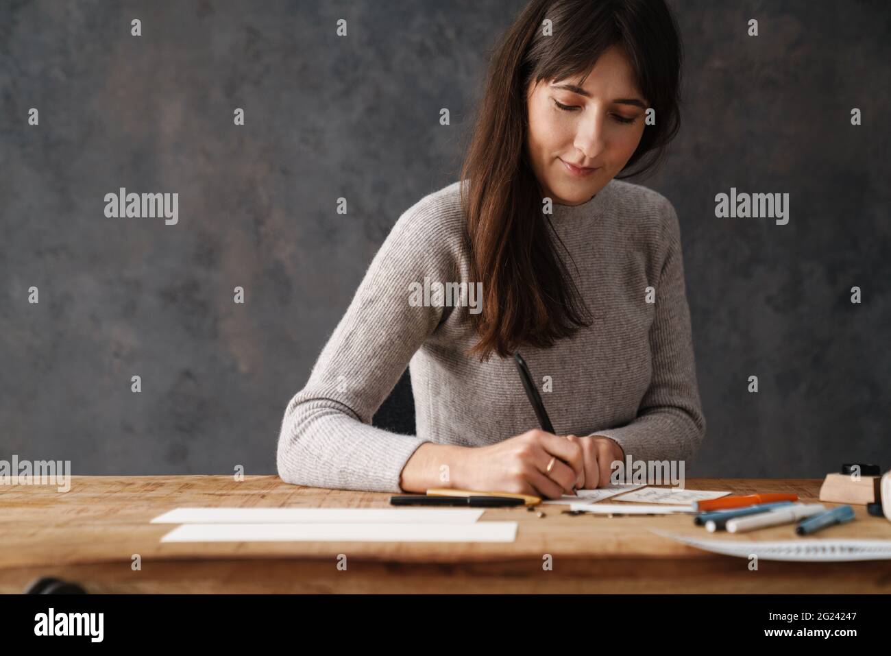 Serious beautiful calligrapher girl writing while working at table ...